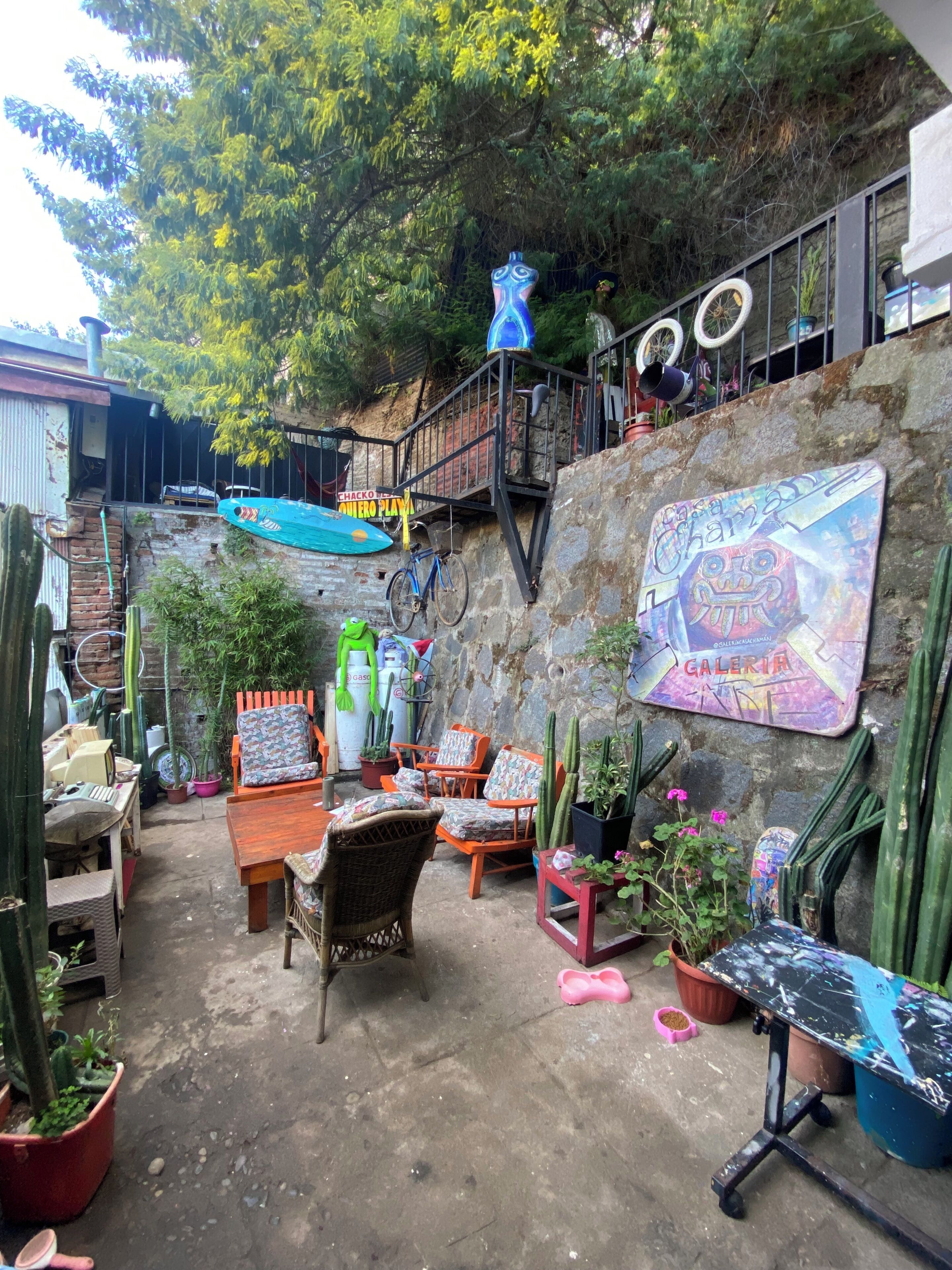 Um espaço de pátio com móveis de exterior, uma bicicleta e um mural na parede.