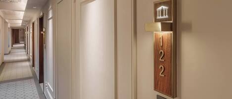 Corredor de hotel com placa de número 22, interruptor de luz e decoração no teto.