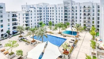 Edifício residencial moderno com piscina no terraço e vegetação ao redor.