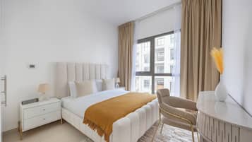 Quarto moderno com cama, mesas de cabeceira, uma cadeira e vista para o exterior.