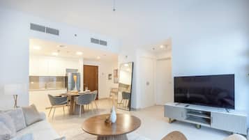 Uma sala de estar moderna com televisão de tela plana, área de jantar e cozinha.