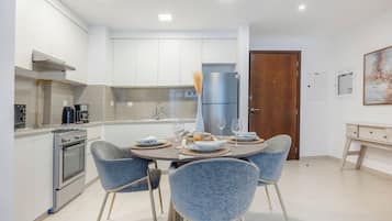 Cozinha moderna com armários brancos, forno embutido e área de jantar com mesa redonda e quatro cadeiras.
