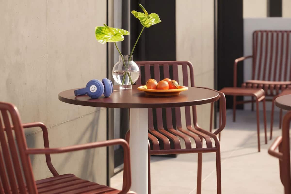 Uma mesa redonda com um vaso de flores, um prato de frutas e um par de fones de ouvido.