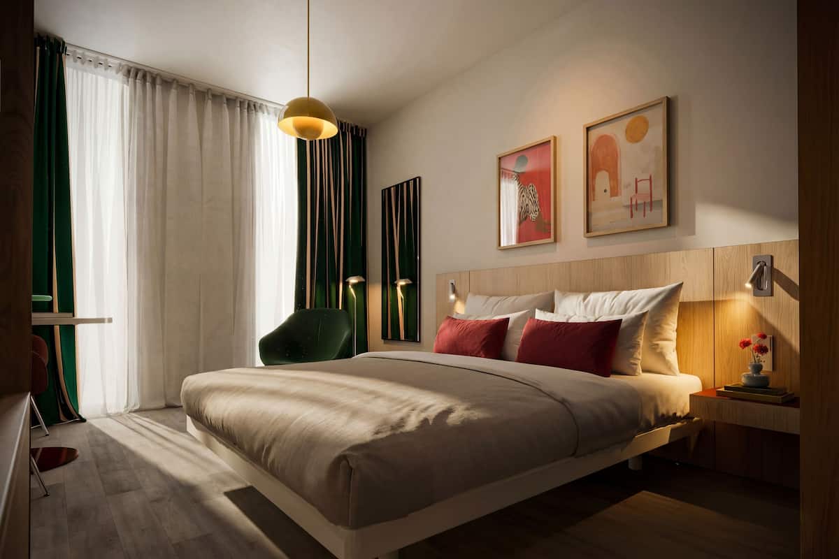 Quarto moderno com uma cama grande, uma cadeira verde, mesa de cabeceira com abajur e uma obra de arte na parede.