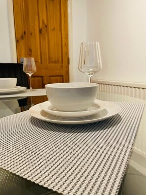 Mesa de jantar com uma tigela branca e uma taça de vinho sobre um jogo americano estampado.