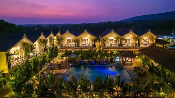 Resort com várias acomodações no estilo bangalô, piscina central e paisagismo tropical exuberante.