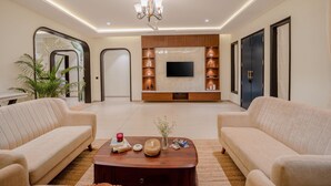 Uma sala de estar moderna com dois sofás, uma mesa de centro, uma televisão e um aparador de madeira.