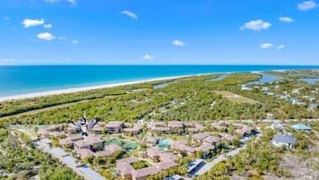 Vista aérea de um resort com vários edifícios, piscina e praia.