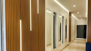 Um corredor moderno com ripas verticais de madeira, iluminação embutida e painéis espelhados nas paredes.