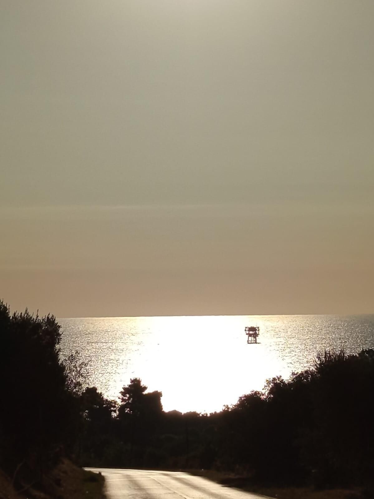 Uma estrada que leva a um corpo de água, com um barco ao longe.