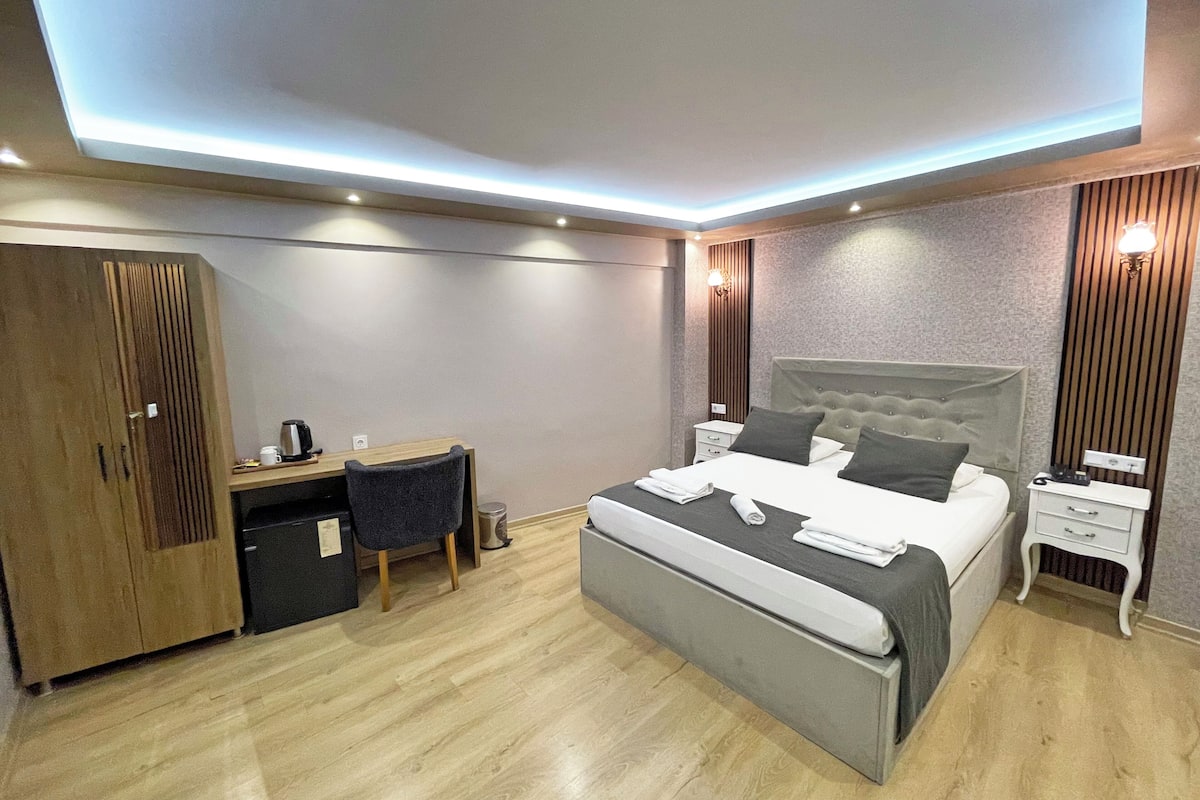 Quarto de hotel moderno com uma cama grande, uma escrivaninha, um guarda-roupa e um pequeno espaço para sentar.