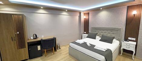 Quarto de hotel moderno com uma cama grande, uma escrivaninha, um guarda-roupa e um pequeno espaço para sentar.