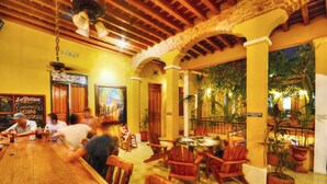 Um restaurante com mobiliário de madeira, piso xadrez e plantas em vasos.