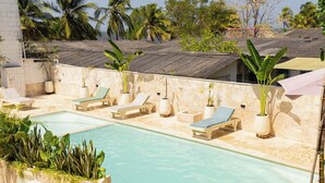 Uma área de piscina com espreguiçadeiras e plantas em vasos.