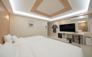 Quarto de hotel moderno com uma cama grande, televisão de tela plana, escrivaninha com cadeira e um espelho.