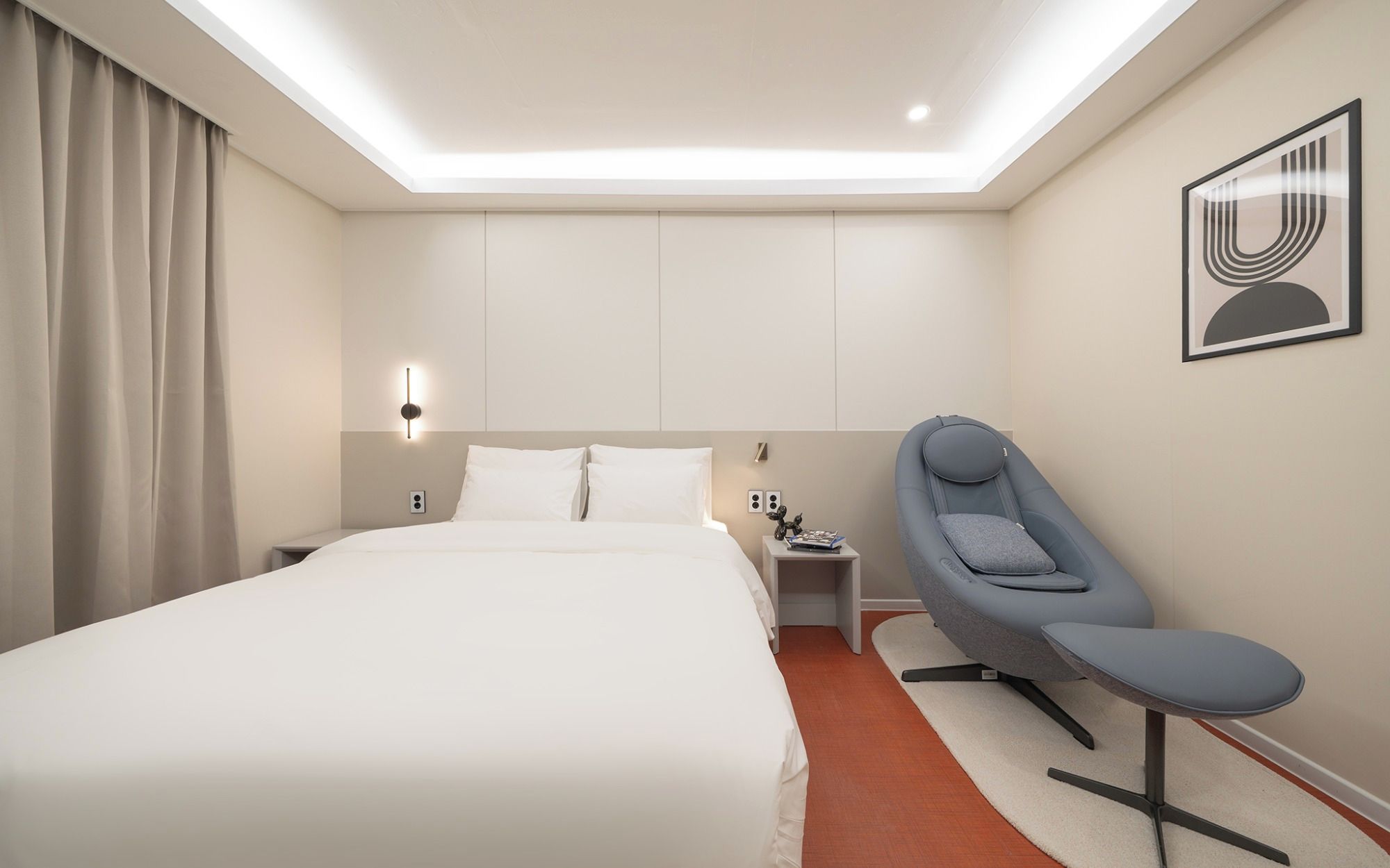 Quarto de hotel moderno com uma cama, área de estar e uma obra de arte na parede.