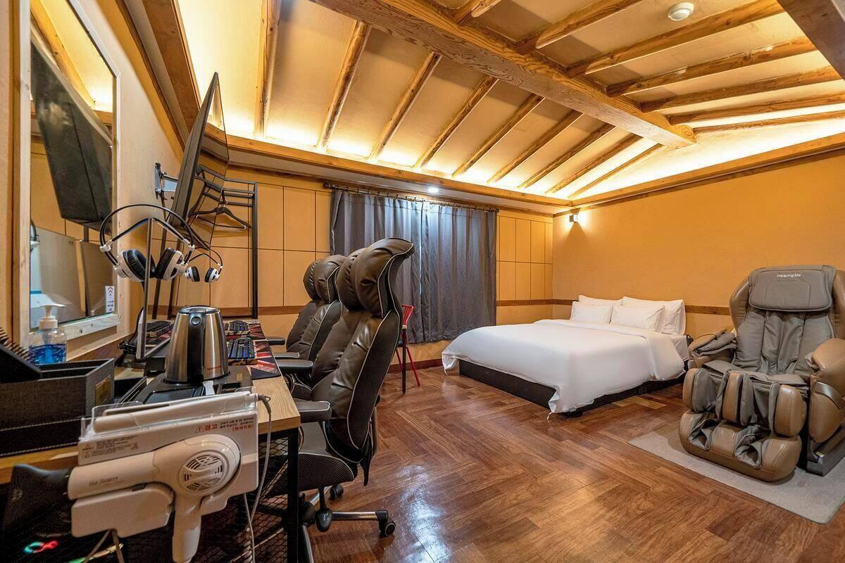 Quarto de hotel com cama, cadeira de massagem, secretária com auscultadores e espelho.