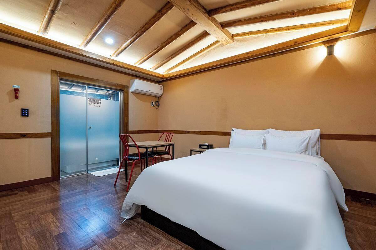 Quarto de hotel com cama, escrivaninha, cadeira e porta.