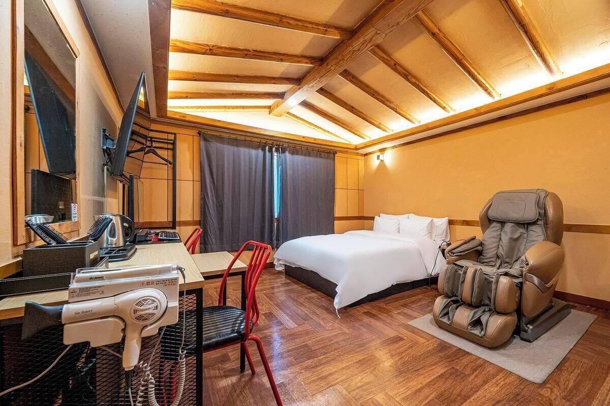 Quarto de hotel com cama, cadeira de massagem, secretária com secador de cabelo e um espelho.