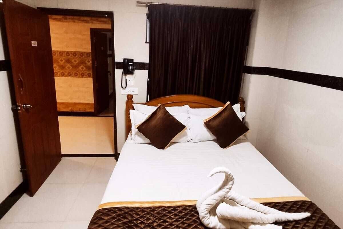 Quarto de hotel com cama, telefone, cortina e porta.
