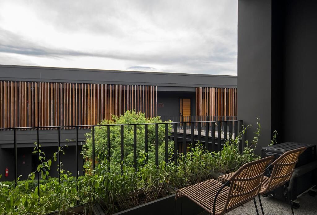 Varanda com vista para um edifício, corrimão e vegetação.