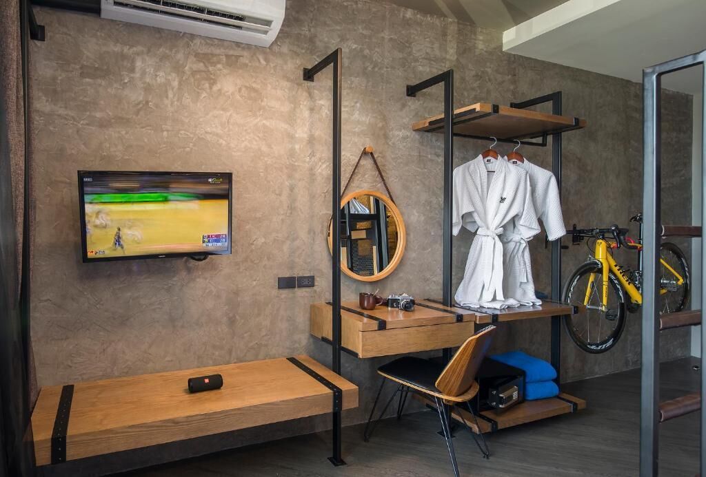 Quarto moderno com televisão, móveis de madeira, uma bicicleta e um espelho.