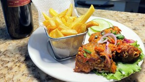 Um prato com frango frito, batatas fritas e uma garrafa de vinho Carlo Rosi em uma bancada de cozinha.