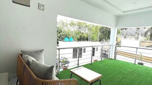 Quarto com sofá de vime, uma mesinha e piso de grama artificial.