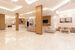 Um hall de hotel moderno com balcão de recepção, sofás, mesa de centro e obras de arte nas paredes.