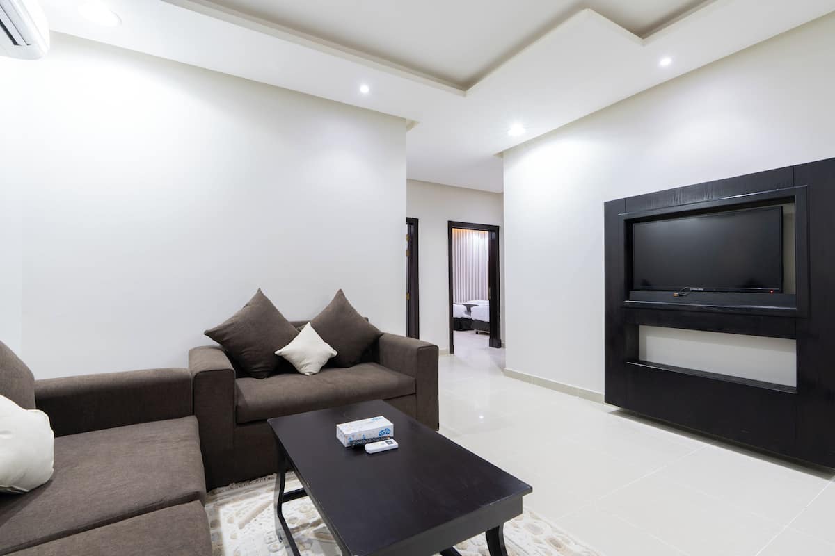 Uma sala de estar moderna com um sofá, uma mesa de centro e uma TV de tela plana fixada na parede.