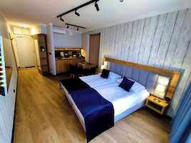 Quarto de hotel com cama, mesa de cabeceira e área de kitchenette.