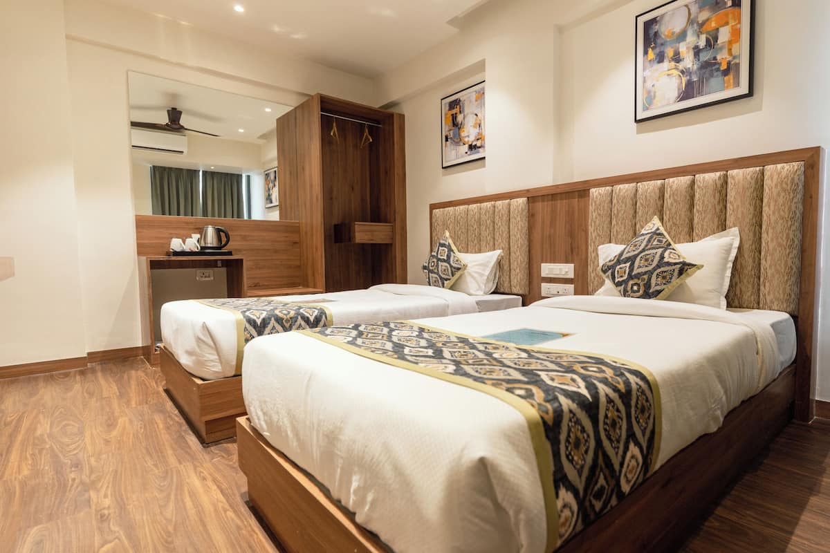 Quarto de hotel com duas camas, um guarda-roupa de madeira, um espelho e arte abstrata nas paredes.