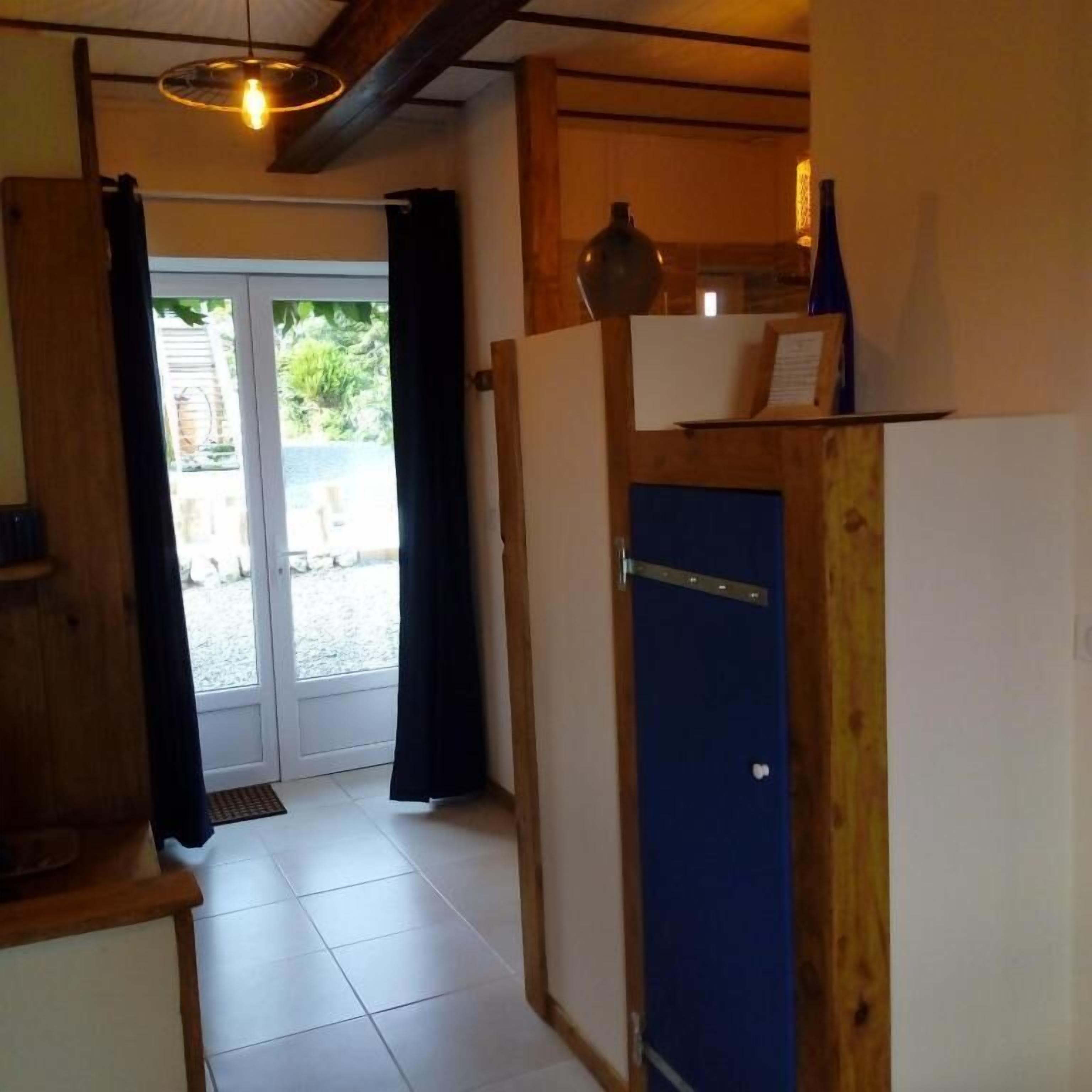Um corredor com uma porta de madeira, um armário azul e um lustre.