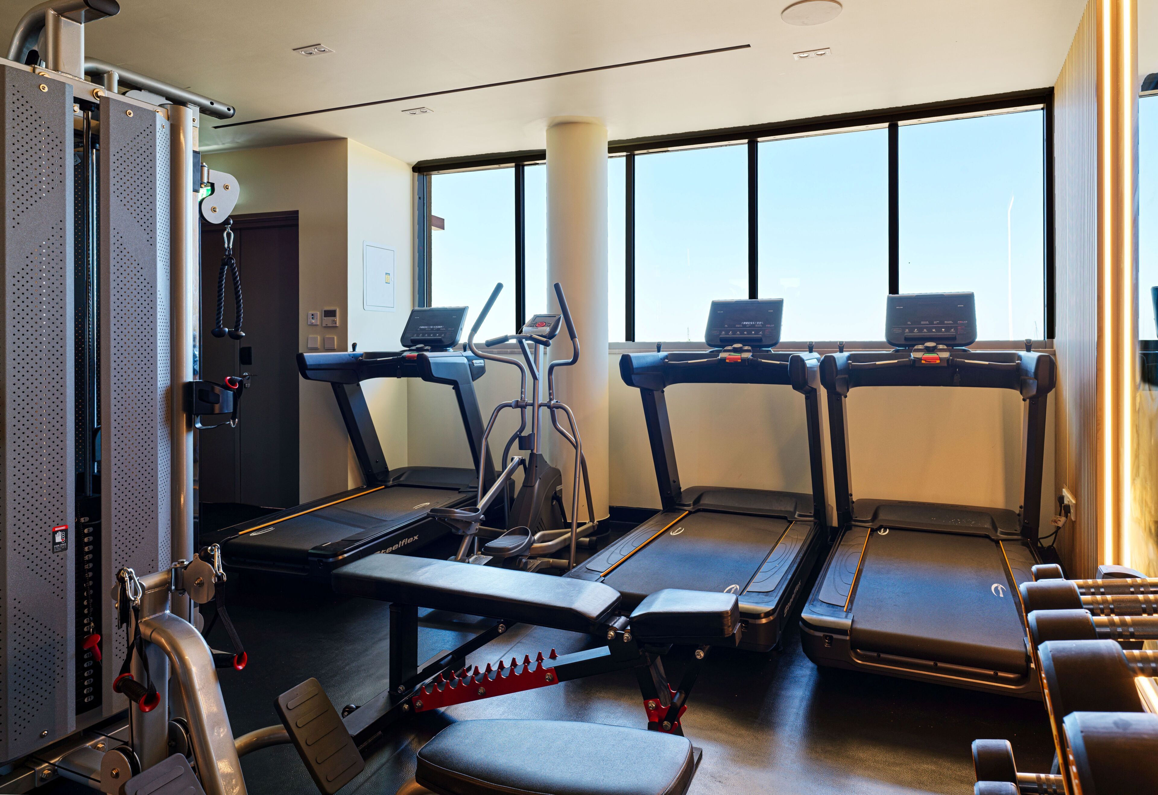 Uma academia com esteiras, bicicletas ergométricas e aparelhos de musculação.