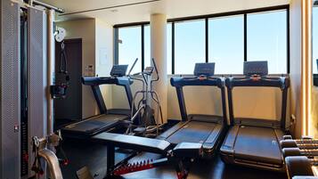 Uma academia com esteiras, bicicletas ergométricas e aparelhos de musculação.