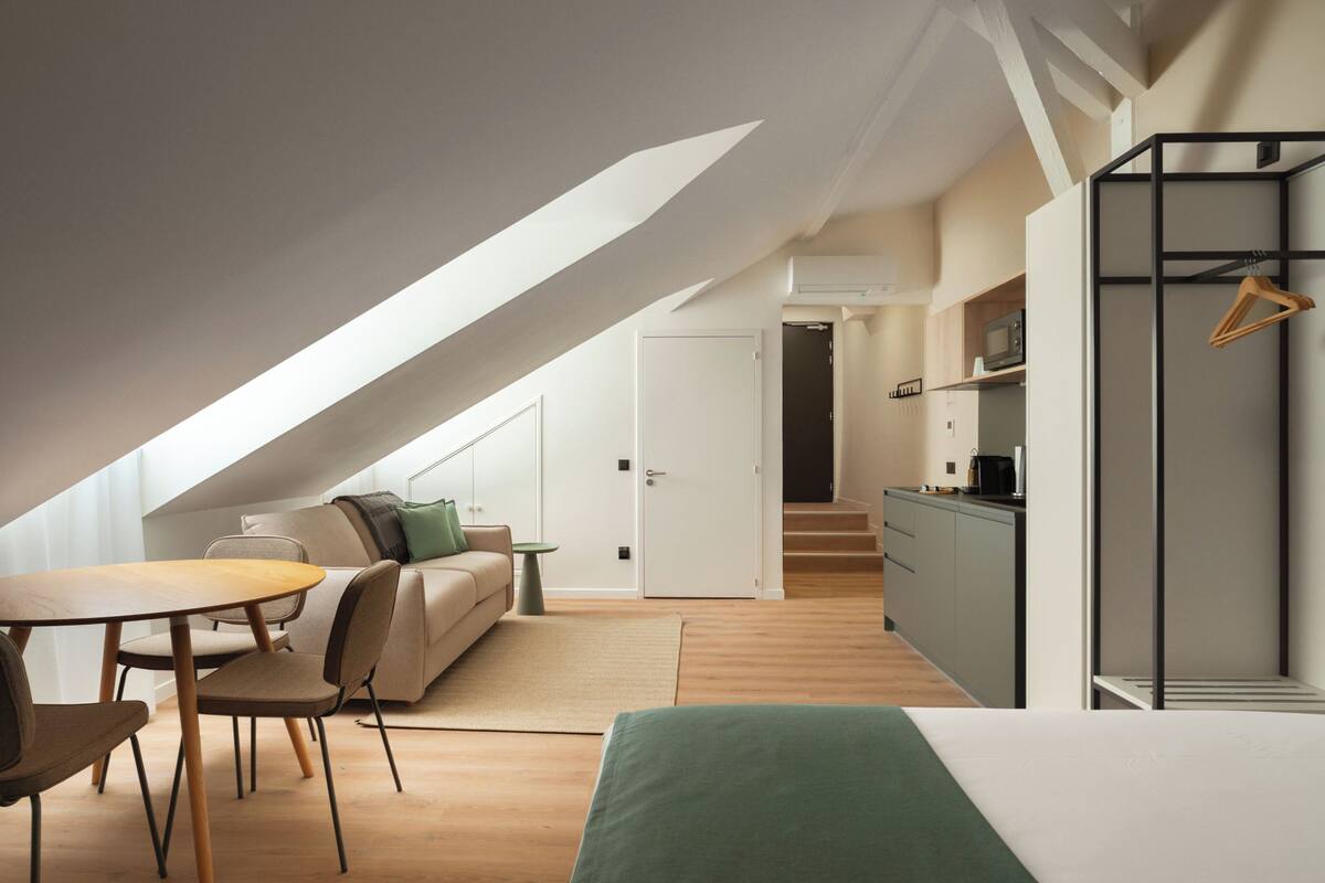 Quarto moderno estilo loft com área de refeições, kitchenette e escada para um andar superior.