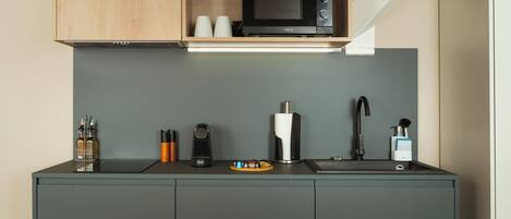 Cozinha moderna com micro-ondas, cafeteira e pia.