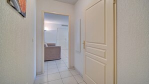 Um corredor com porta, um sofá e um quadro na parede.