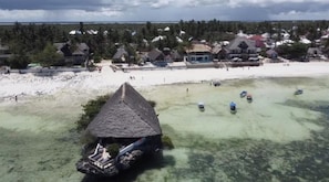 Resort na praia com bangalôs de telhado de palha, águas turquesa cristalinas e uma praia de areia.