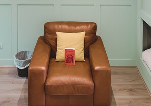 Um sofá de couro marrom com uma almofada amarela e um livro intitulado 