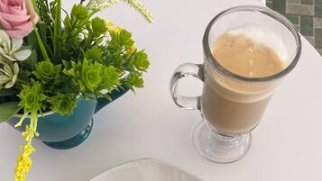 Prato de café da manhã com ovos mexidos, abacate, queijo, uma pequena tigela de manteiga, plantains fritos e uma xícara de café.