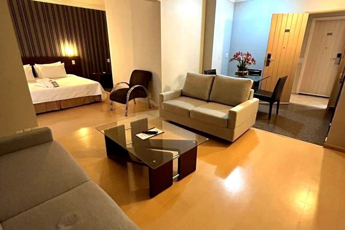 Sala de estar moderna com sofá, mesa de centro e área de jantar com mesa e cadeiras.