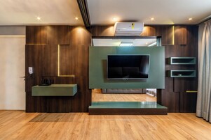 Uma sala de estar moderna com televisão de tela plana, estantes embutidas e piso de madeira.