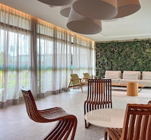 Uma sala de estar moderna com uma janela grande, um sofá, uma mesa de centro e cadeiras de madeira.
