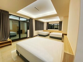 Quarto de hotel moderno com uma cama grande, uma escrivaninha e uma porta de vidro deslizante para uma varanda.
