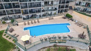 Um edifício com vários andares, área de piscina, espaço para sentar ao ar livre e uma placa com a inscrição 'CEDAR HEIGHTS'.