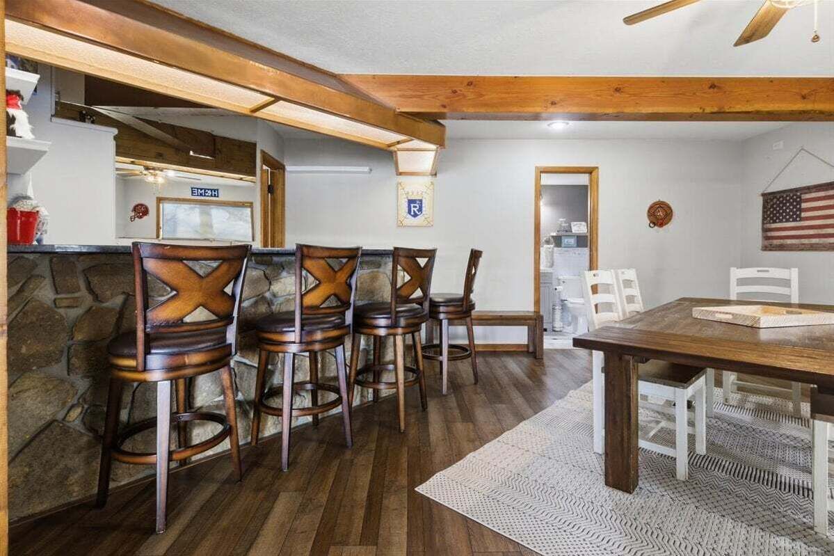 Uma sala de jantar com uma mesa de madeira e quatro cadeiras, uma parede de pedra e uma bandeira na parede.