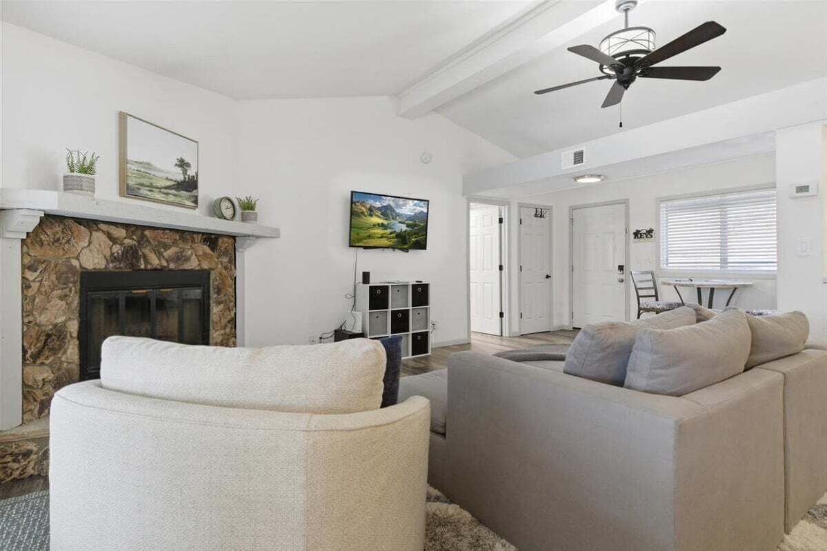 Uma sala de estar com lareira, ventilador de teto e um sofá.