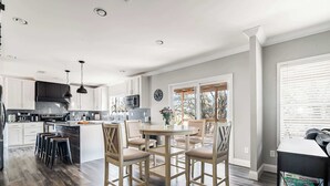 Uma cozinha moderna com ilha central, banquetas de bar e mesa de jantar.