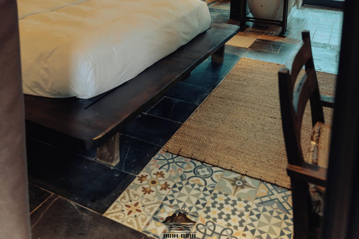 Quarto com cama, uma cadeira, uma mesinha e vista para o exterior.